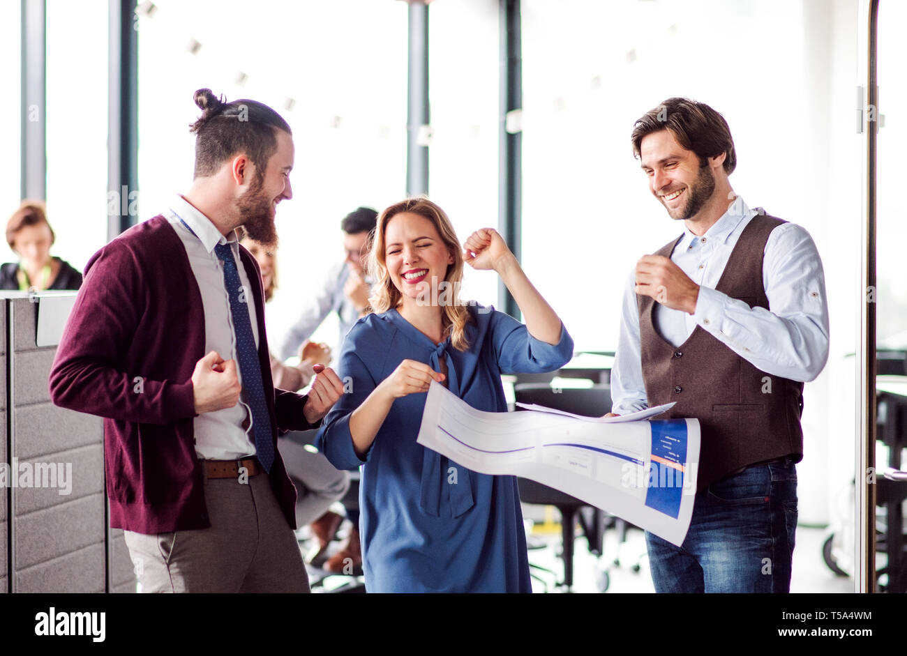A group of young business people in an office, expressing excitement ...