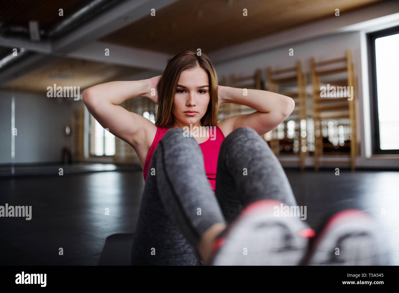 A portrait of a beautiful young girl or woman doing exercise in a gym ...