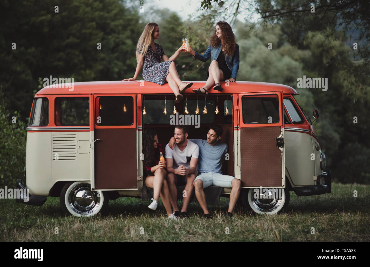 A group of friends at dusk outdoors on a roadtrip through countryside ...