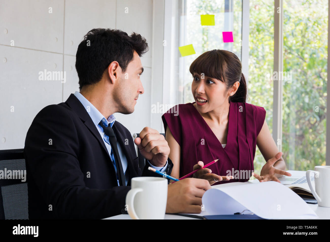 Two multi-ethnic business people in formal suit having the astonishing ...