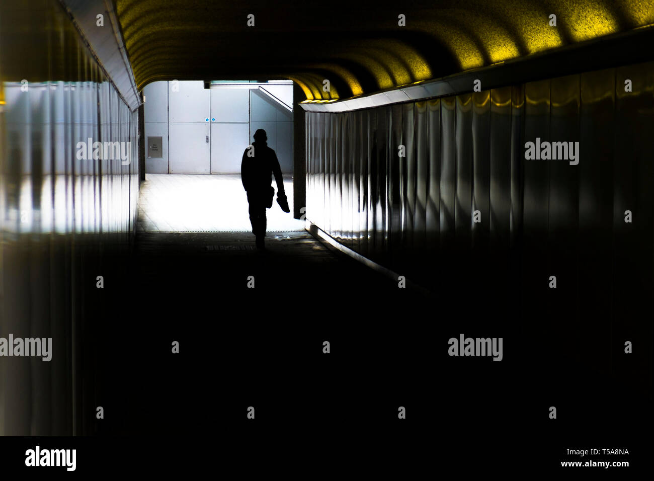 The silhouette of a man walking through a dark underpass Stock Photo ...