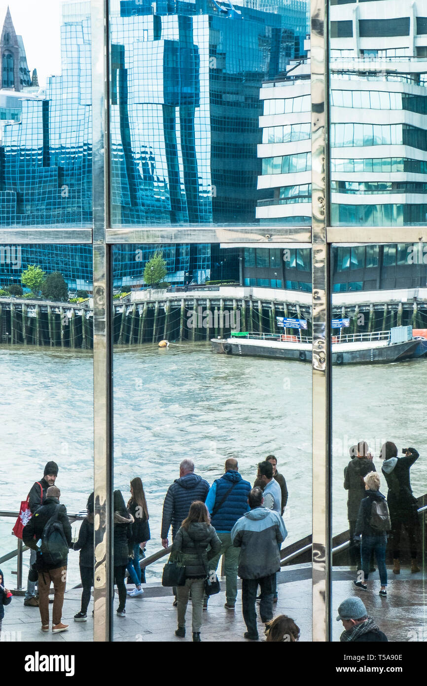 The distorted reflection of people and buildings seen in a large glass ...