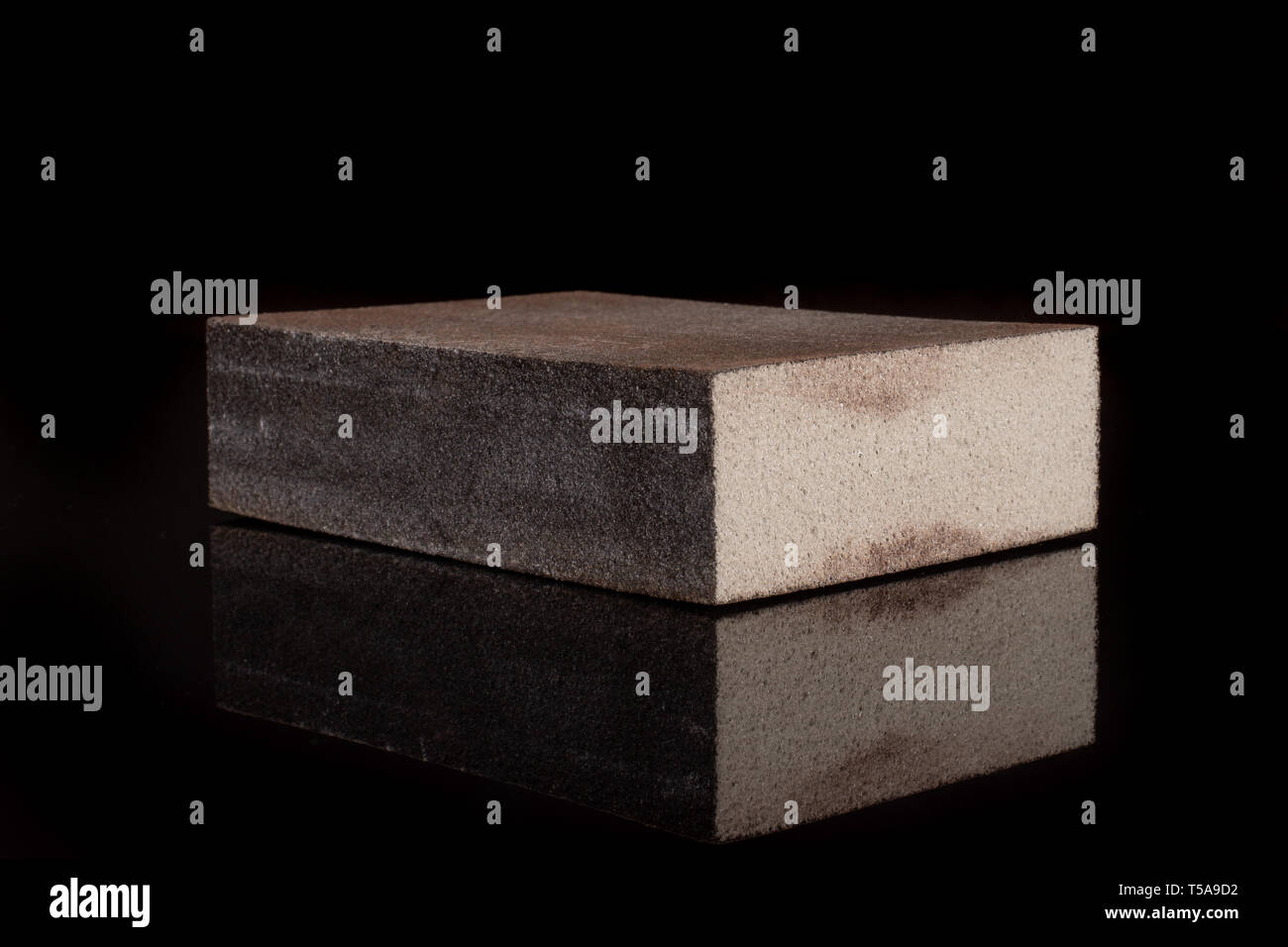 One whole grey abrasive block sponge work item isolated on black glass ...