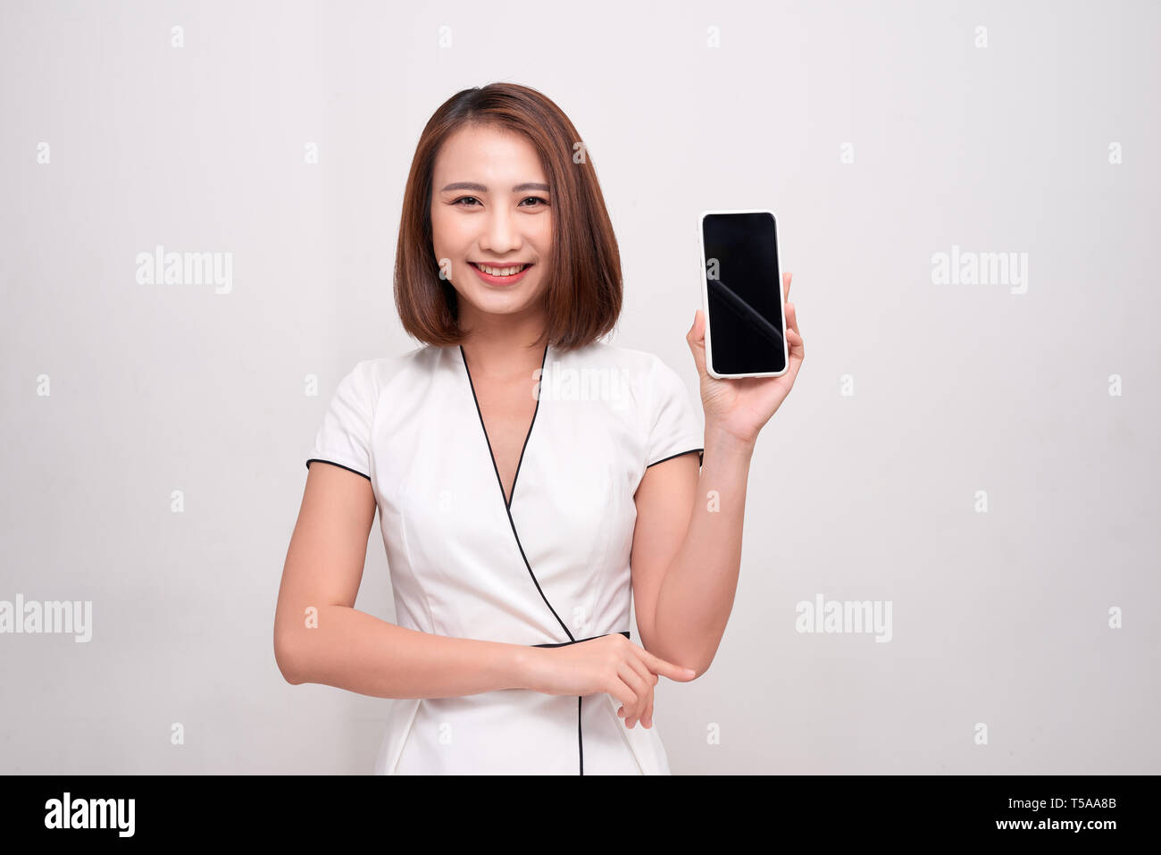 Beautiful Asian woman holding blank screen smartphone on white ...