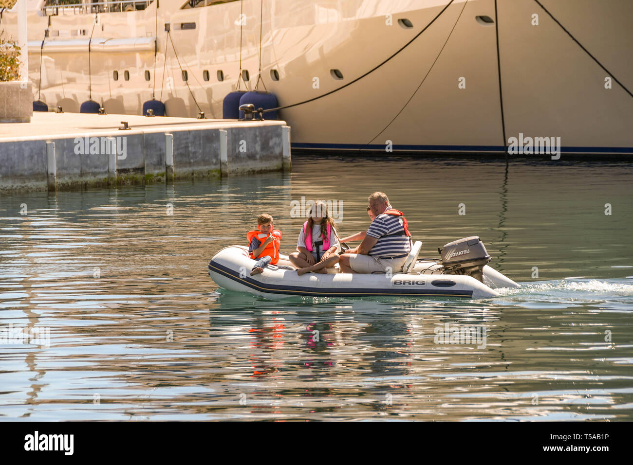 CANNES, FRANCE - APRIL 2019: Family in a small dinghy with outboard ...