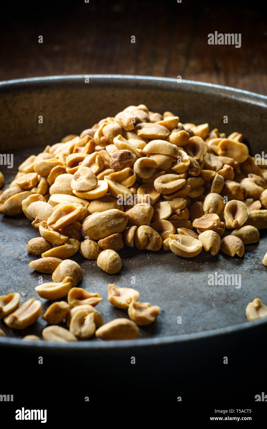 Shelled salty pub peanuts on wooden bar table and dark moody lighting ...
