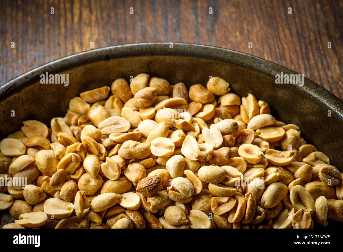 Shelled salty pub peanuts on wooden bar table and dark moody lighting ...