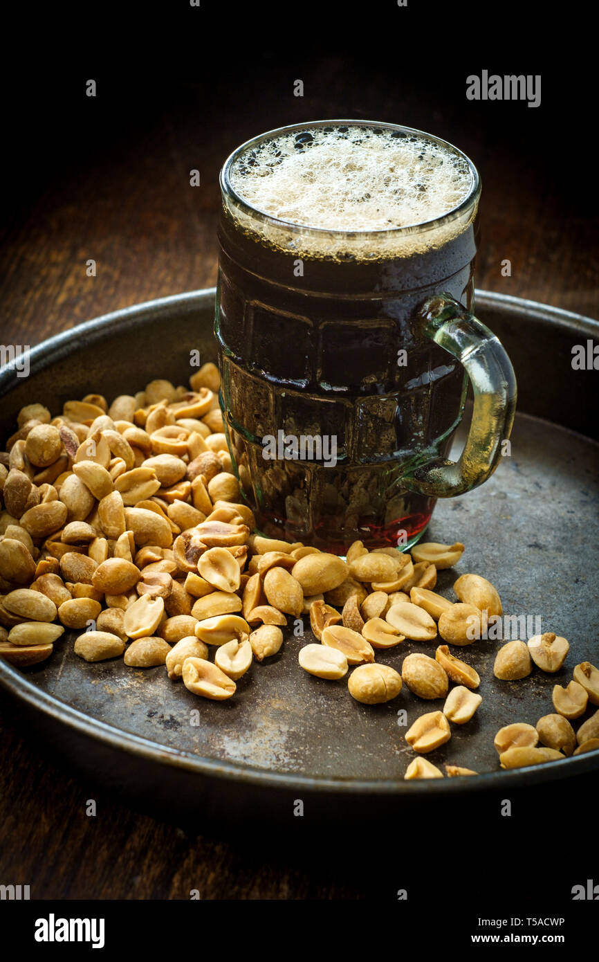 Frothy beer shelled salty pub peanuts on wooden bar table Stock Photo ...