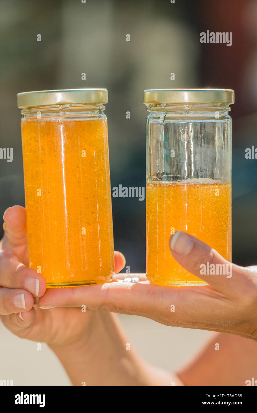 Woman holding jars of honey that were freshly extracted, strained and ...