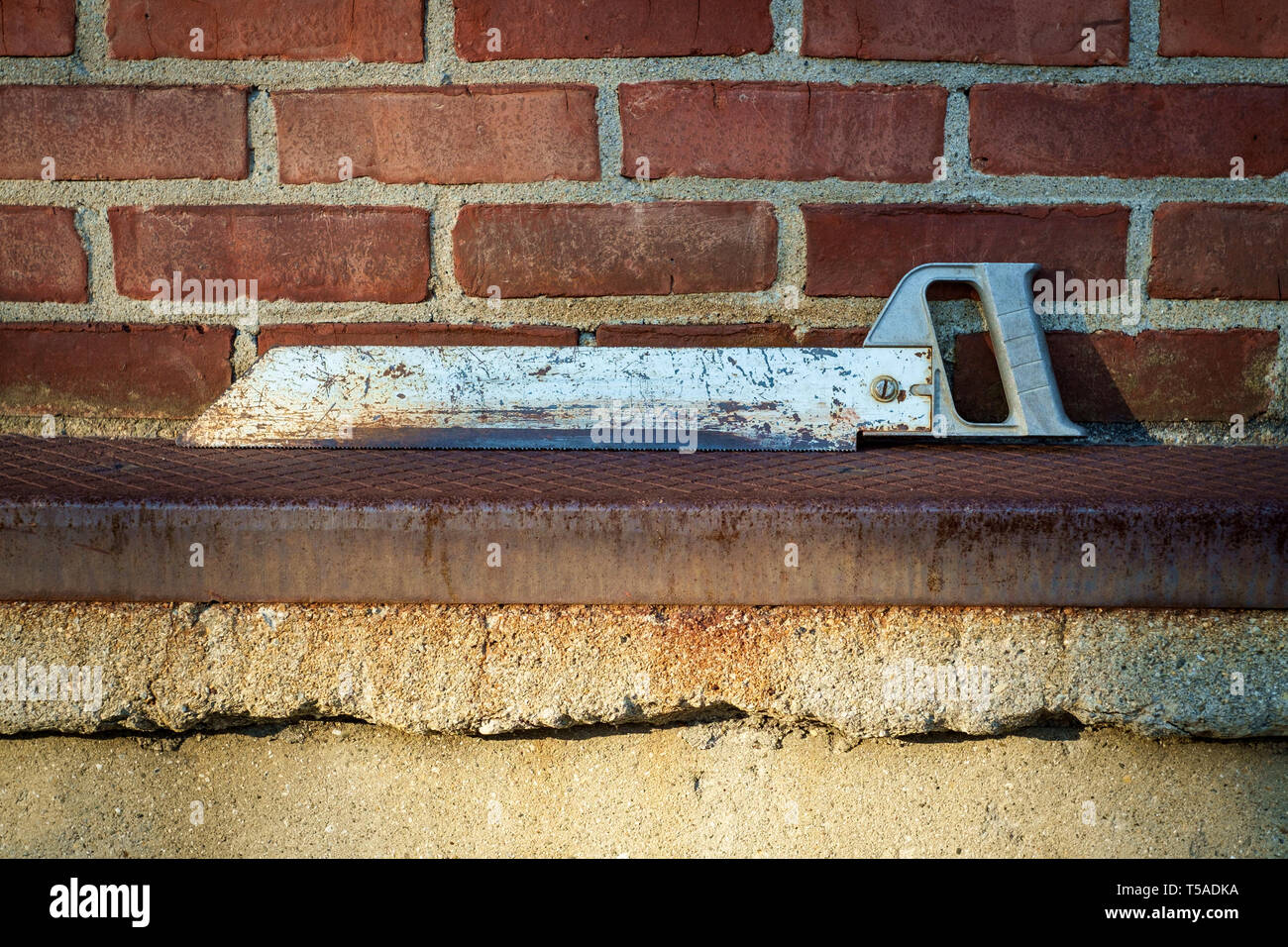 Old rusty construction tool hand saw with grunge brick wall background ...