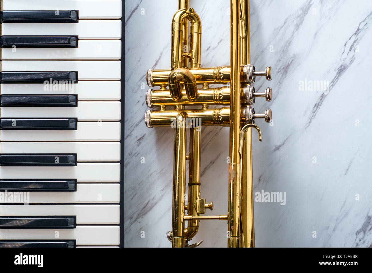 Rusty old classical trumpet on marble table next to electric piano ...