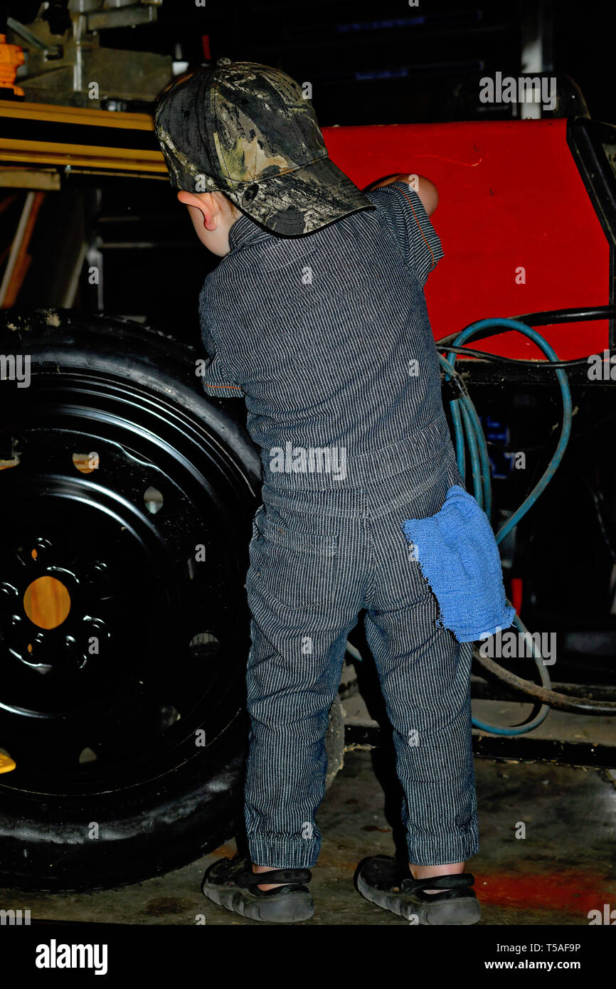Little boy dressed as a mechanic working in a garage Stock Photo - Alamy