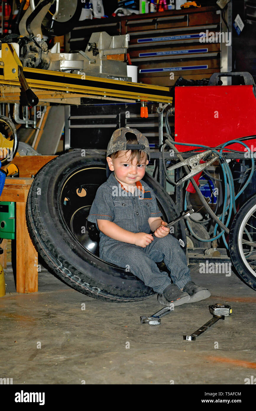 Little boy dressed as a mechanic working in a garage Stock Photo - Alamy