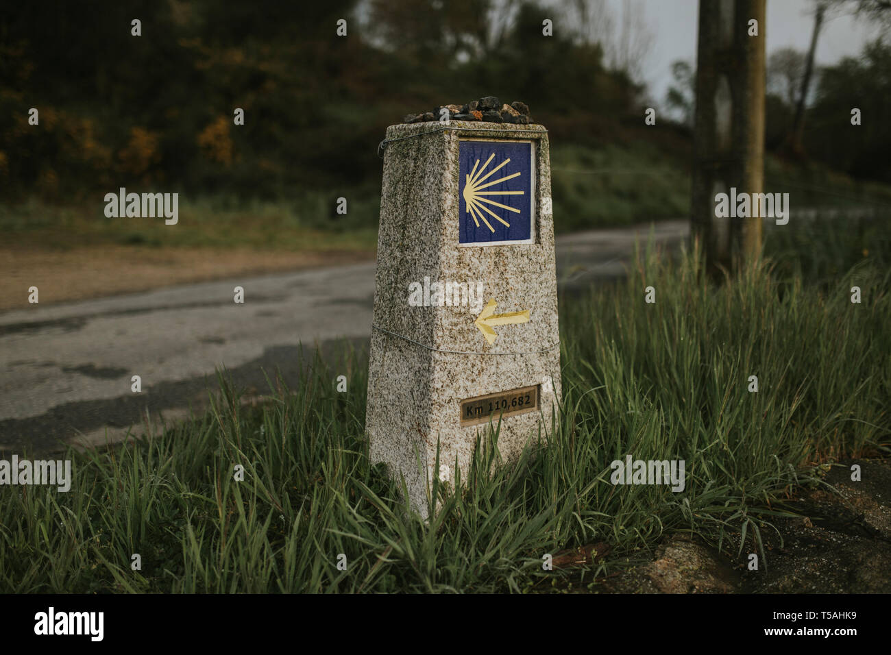 Camino de Santiago post made of stone, with yellow arrow and sign Stock ...