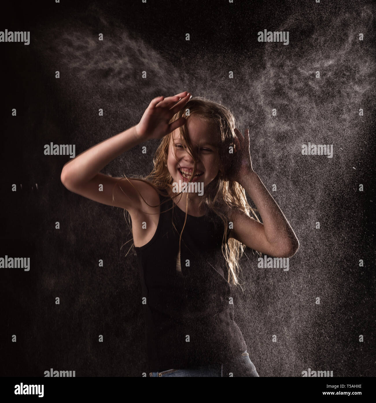 young girl with live emotions dancing under water drops. child ...
