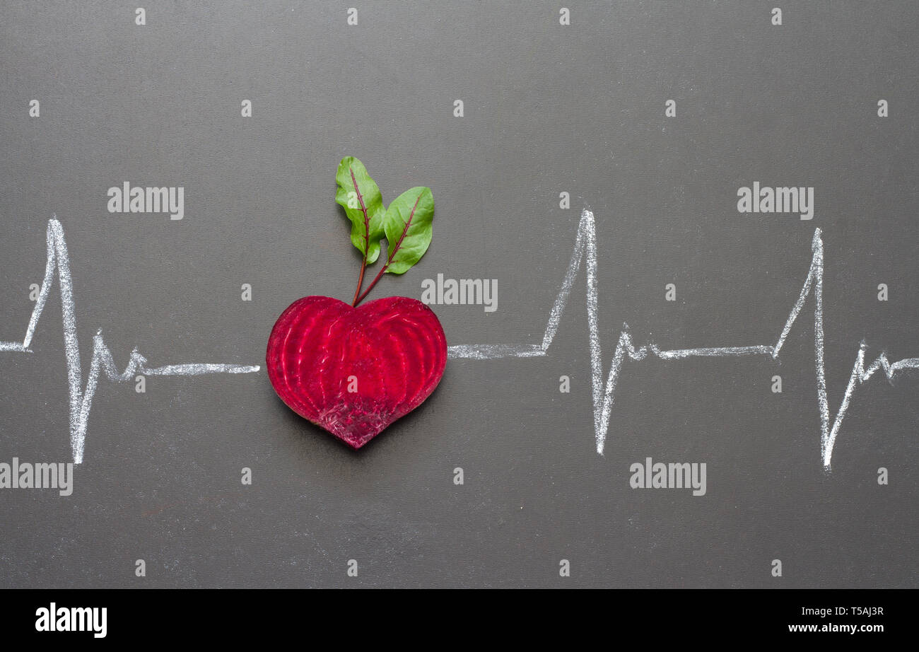 Healthy beetroot with heart shape and electrocardiogram on blackboard ...