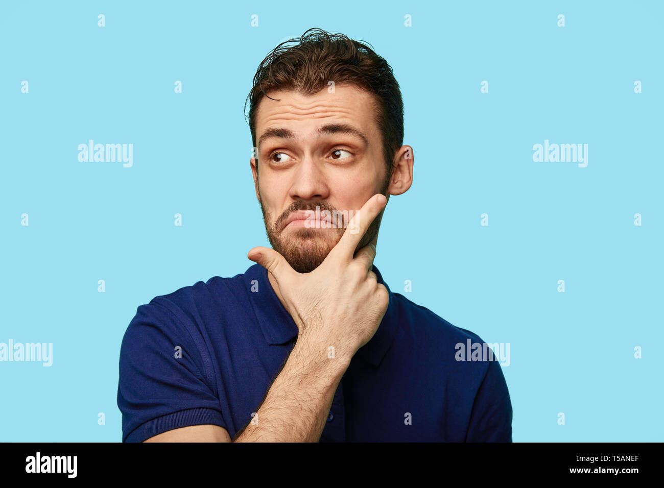 unhappy frustrated male touching his chin while thinking and looking ...