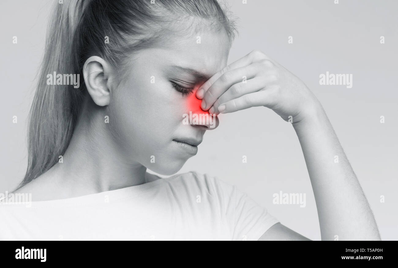 Sad woman holding her nose because sinus pain Stock Photo - Alamy
