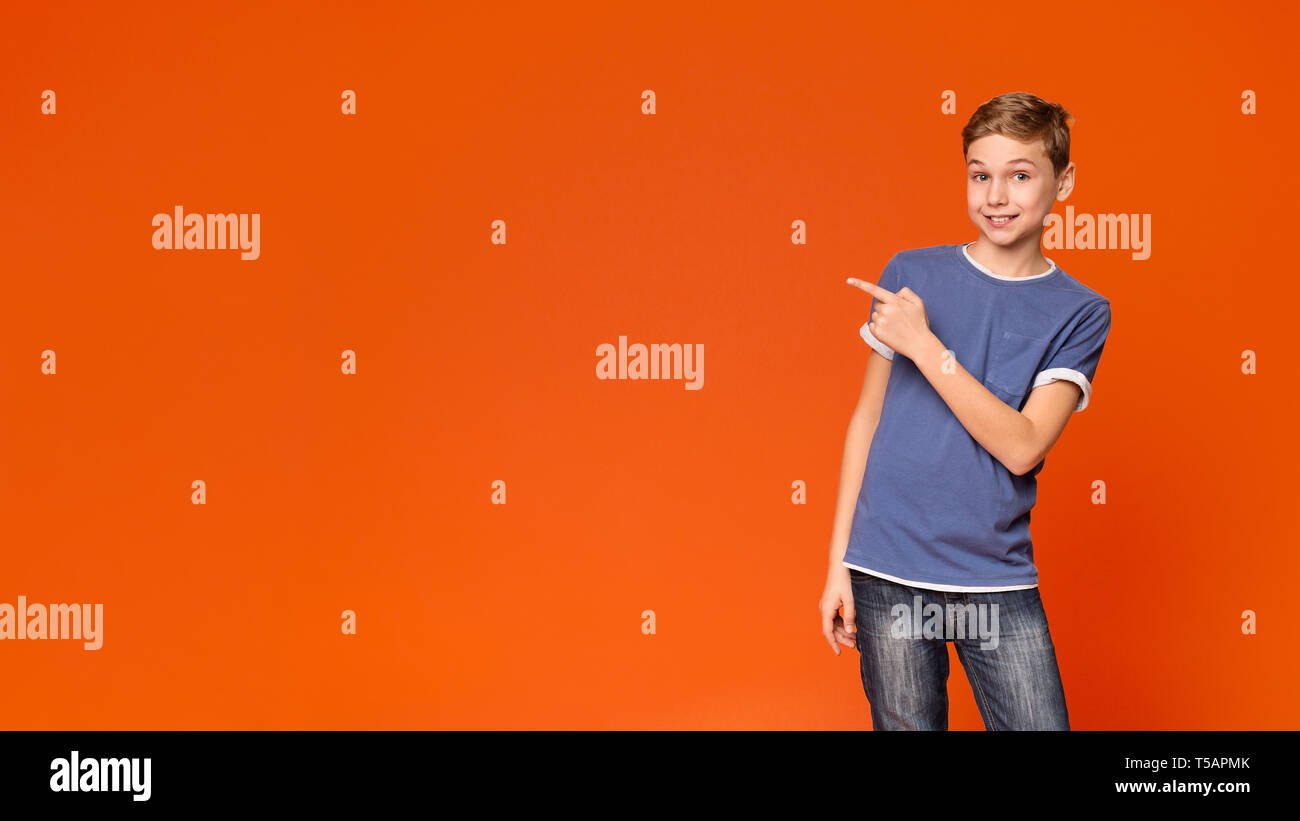 Cute little boy pointing away on orange background Stock Photo - Alamy