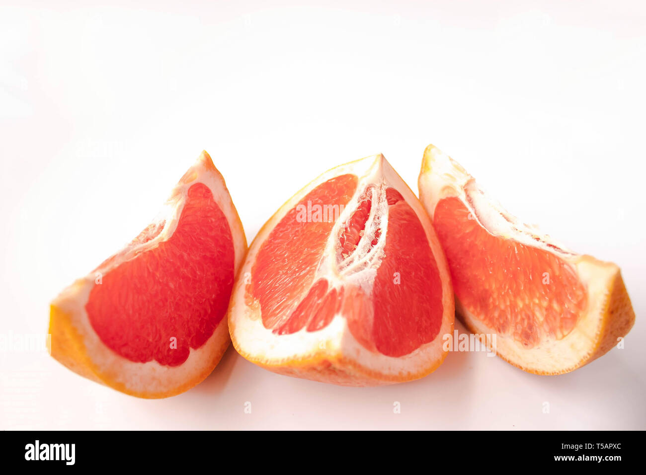 Sliced red grapefruit isolated on white background cut into three ...