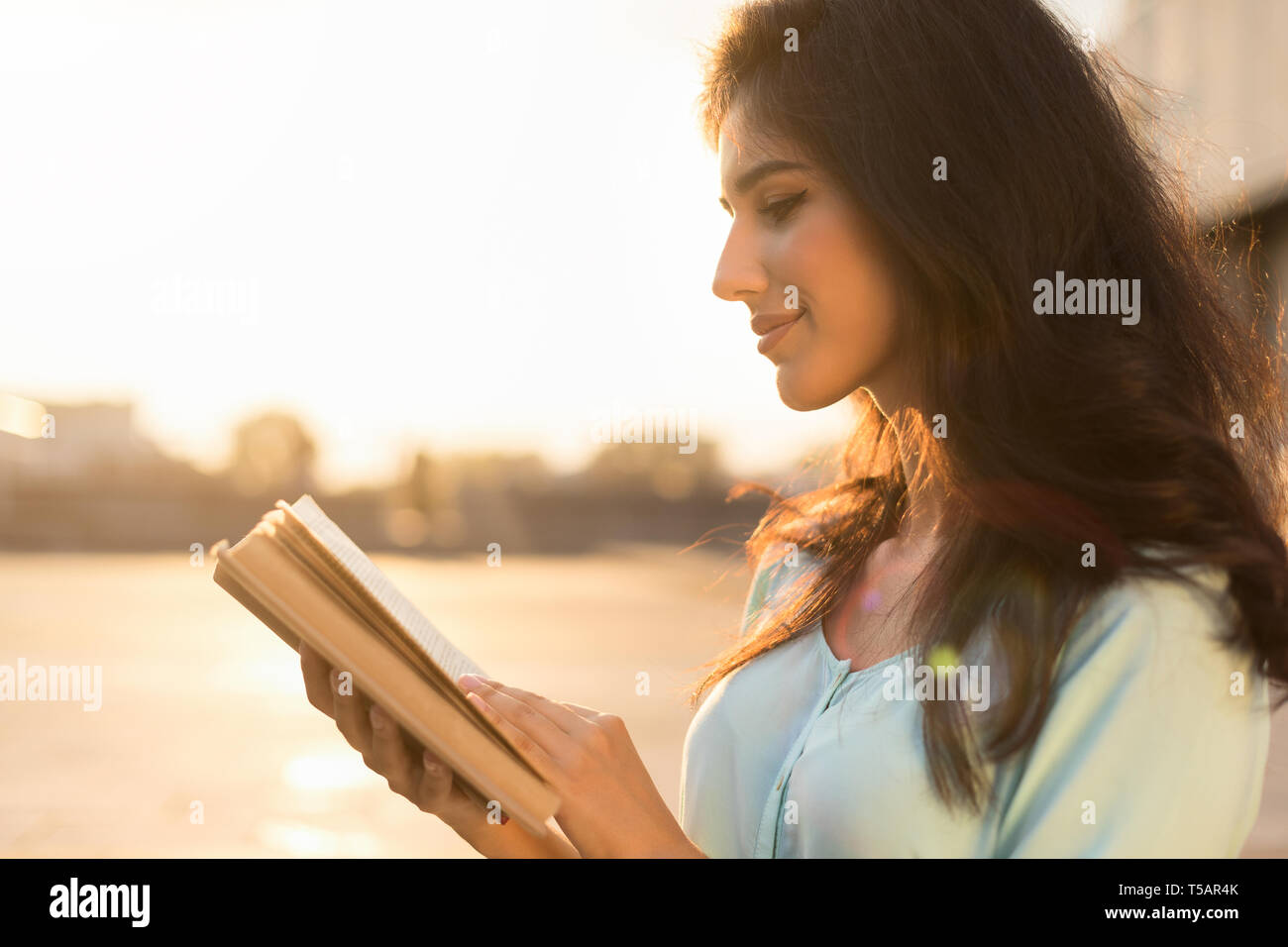 Girl reading book outdoors, enjoying calm evening Stock Photo - Alamy
