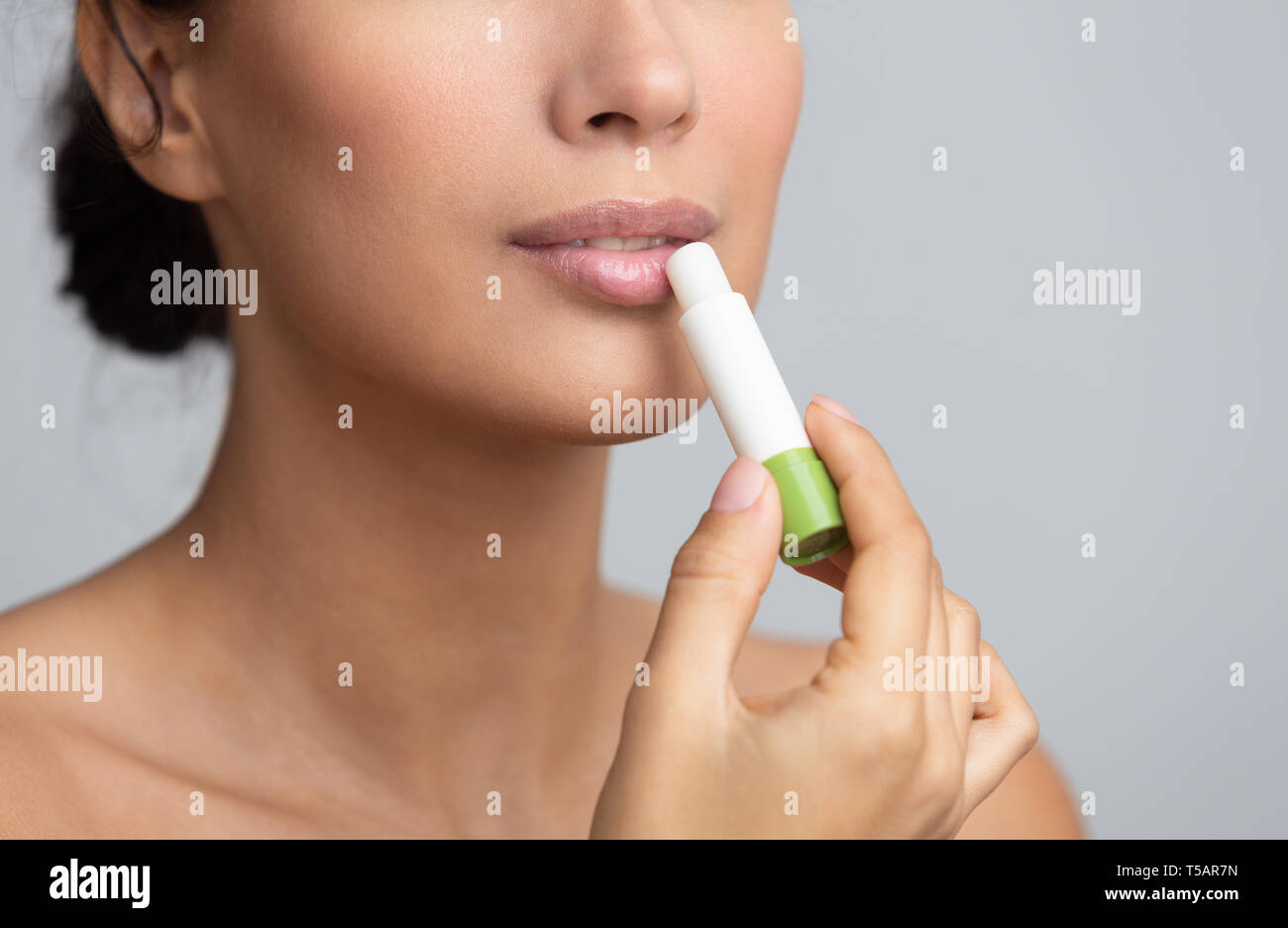 Lips nutrition. Girl applying hygienic balm over grey background Stock ...