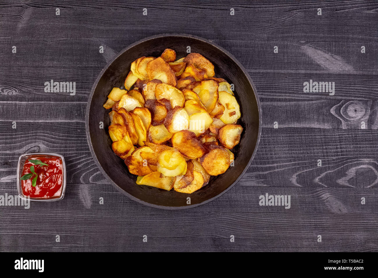 Fried homemade potato chips in a vintage old cast iron pan and tomato ...