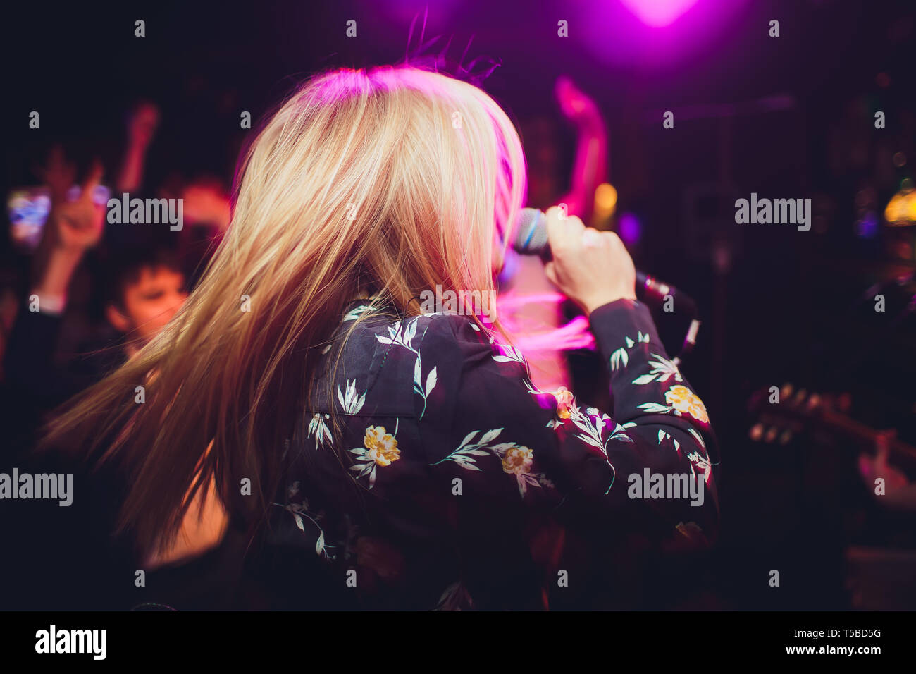 Beauty model girl singer with a microphone singing and dancing over ...