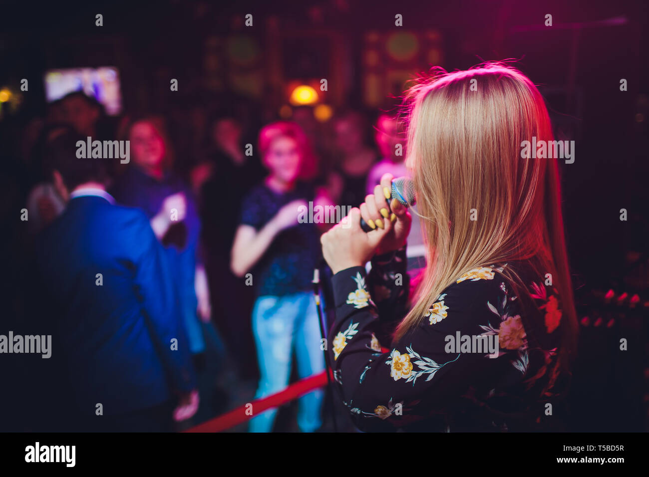 Beauty model girl singer with a microphone singing and dancing over ...