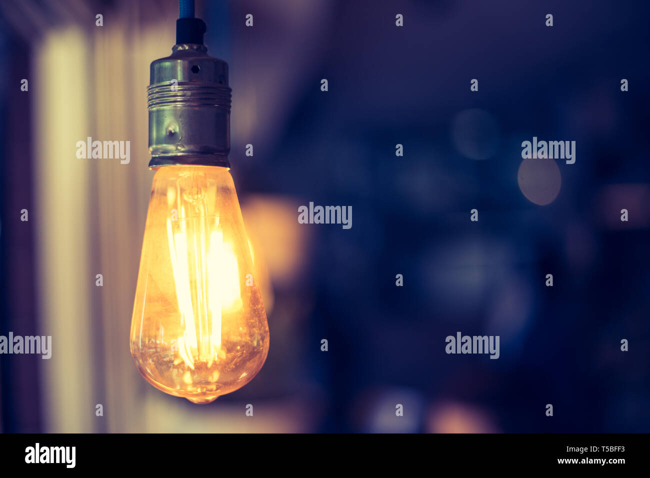 Close up picture of a hanging orange lightbulb in a restaurant or café ...