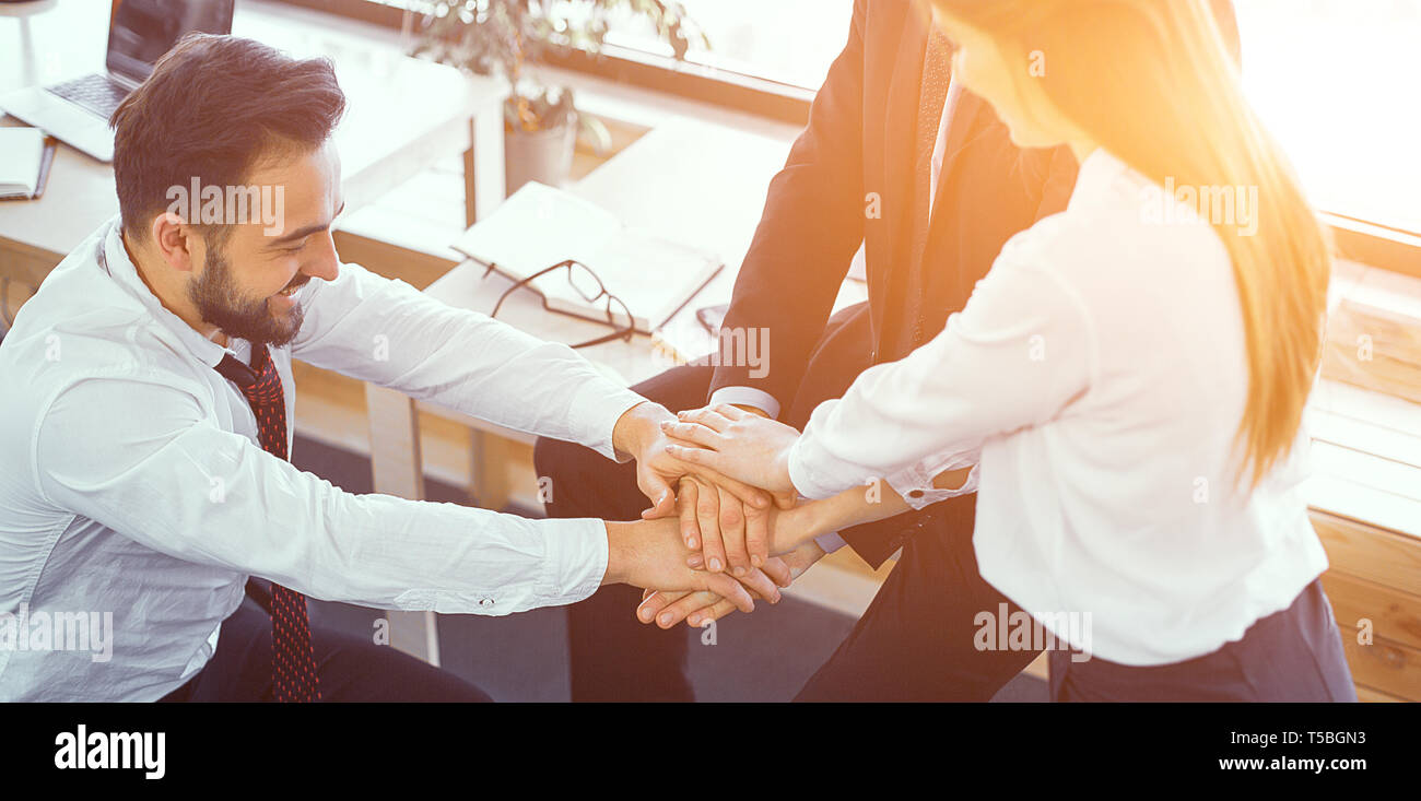 Employees In Sunny Office Railed Hands Together. Expressing Partnership ...