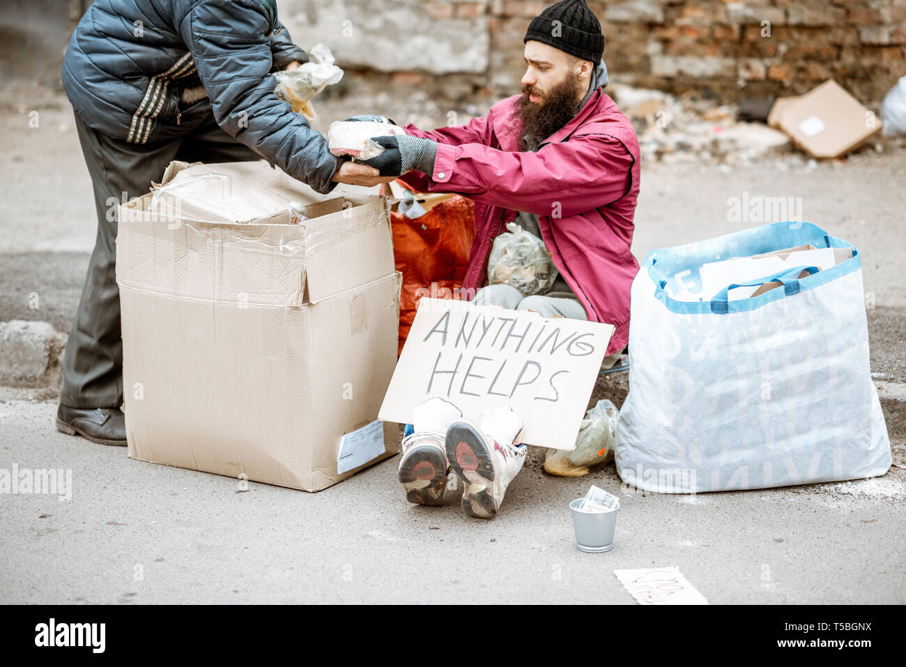 Homeless depressed beggars with bags and some food on the street on the ...