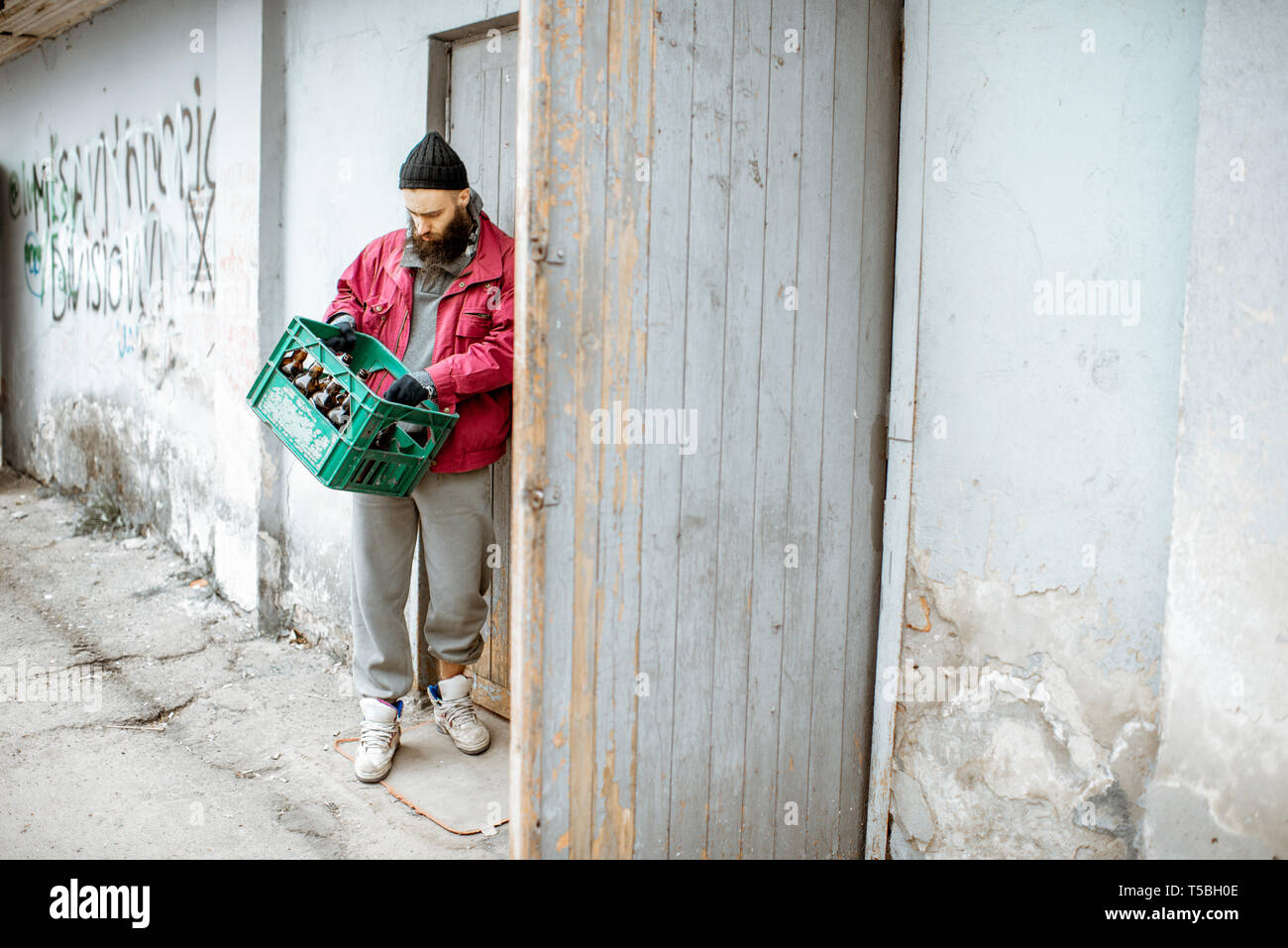 Homeless beggar bringing box with glass bottles to the collection point ...