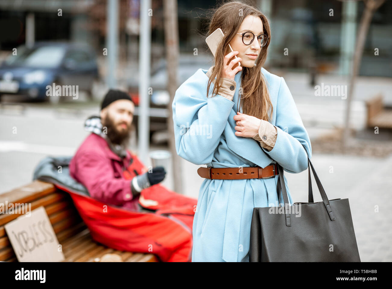 Homeless begging money while sitting on the bench with passing by ...
