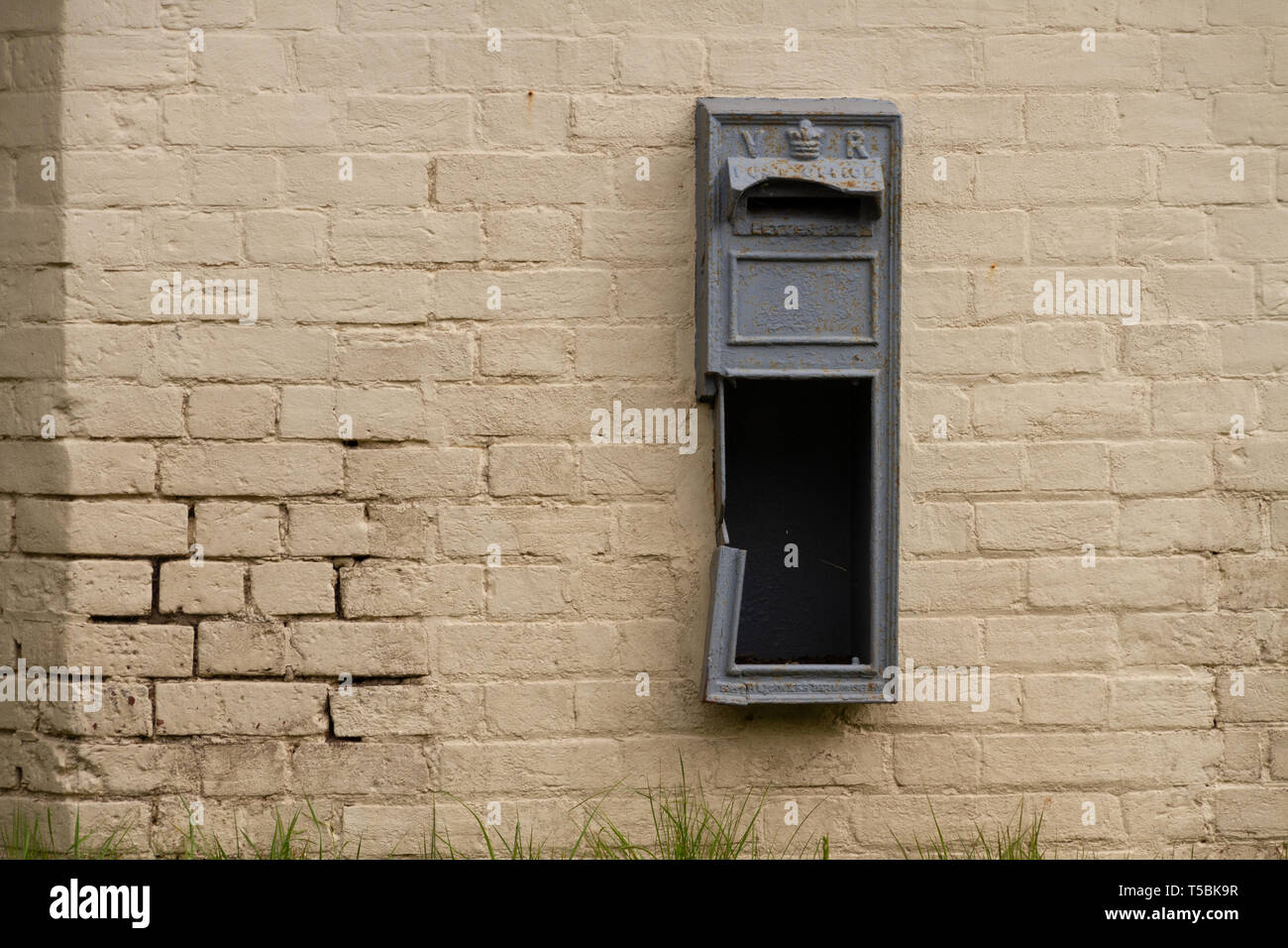 An abandoned Victorian post box with its door missing, painted grey on ...
