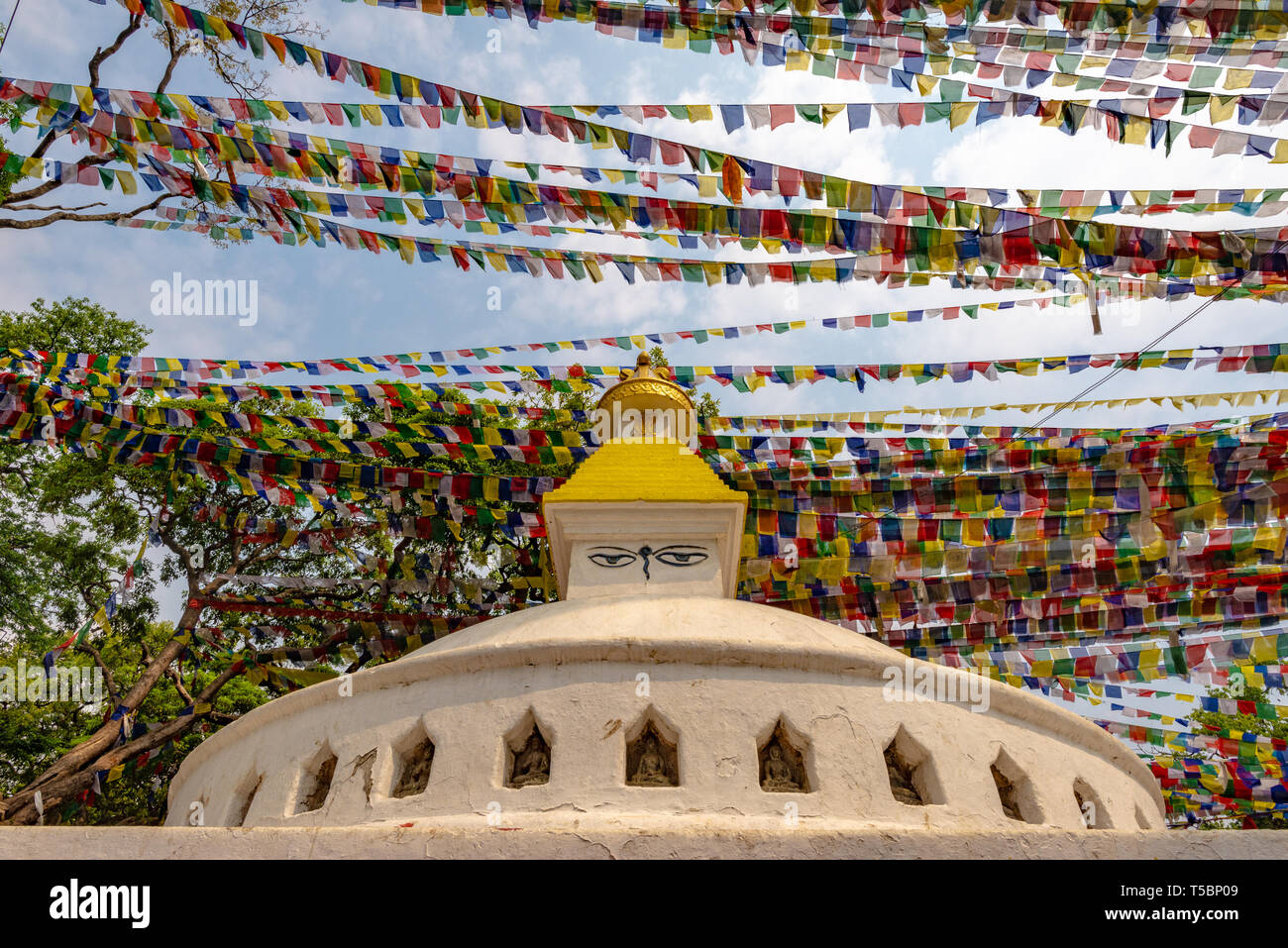 Buddhist stupa and a lot of prayer flags during a partly cloudy spring ...