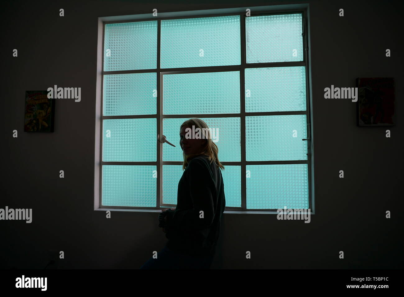 Spooky girl in front of twelve-paned frosted glass turquoise-colored ...