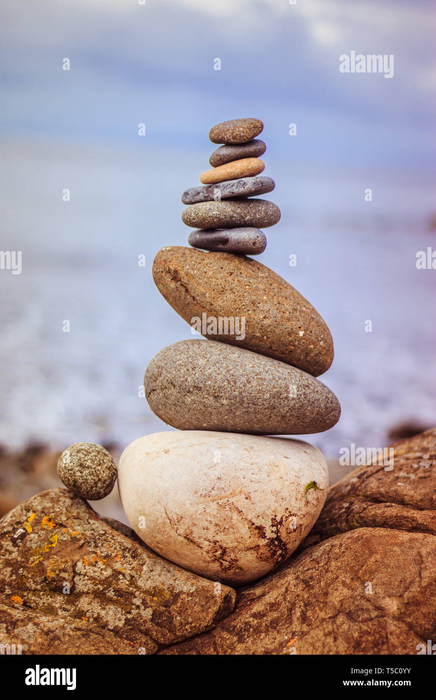 Close up picture of a stone cairn outdoors. Ocean in the blurry ...