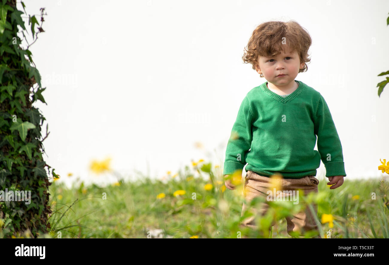 portrait of a young boy with green sweater playing outdoors Stock Photo ...