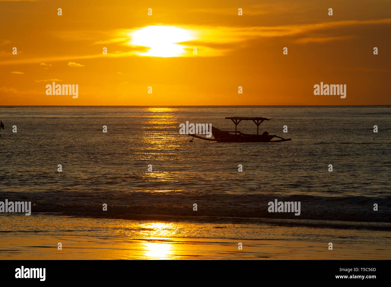 A traditional Balinese Jukung fishing boat during sunset on Jimbaran ...