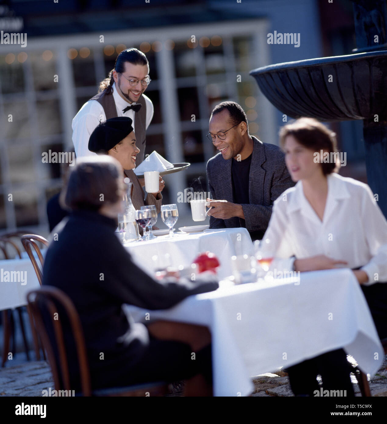 Happy mid adult couple being served by a smiling waiter at their ...
