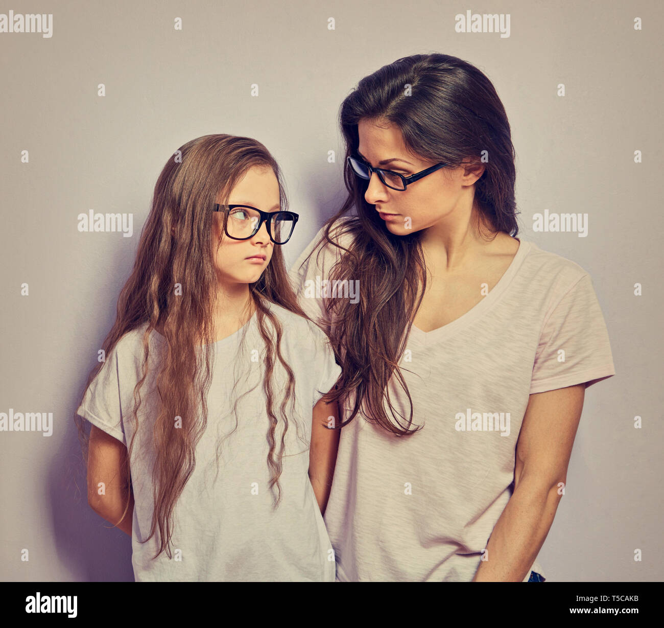 Strict young casual mother looking serious on her cute unhappy offended ...