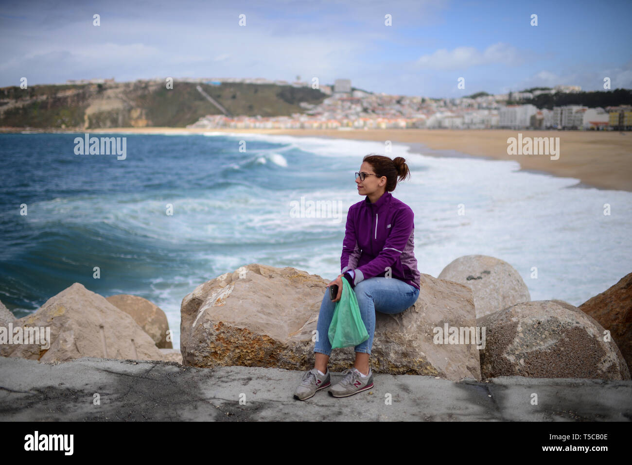 Young woman watches the sea from the dock of Nazare, Portugal Stock ...