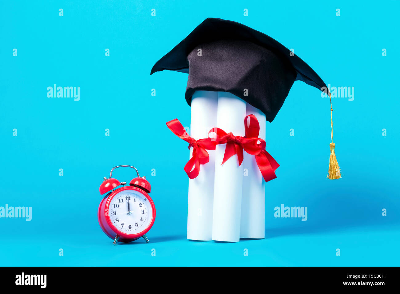 graduation cap on diplomas near red clock, image on a blue background ...