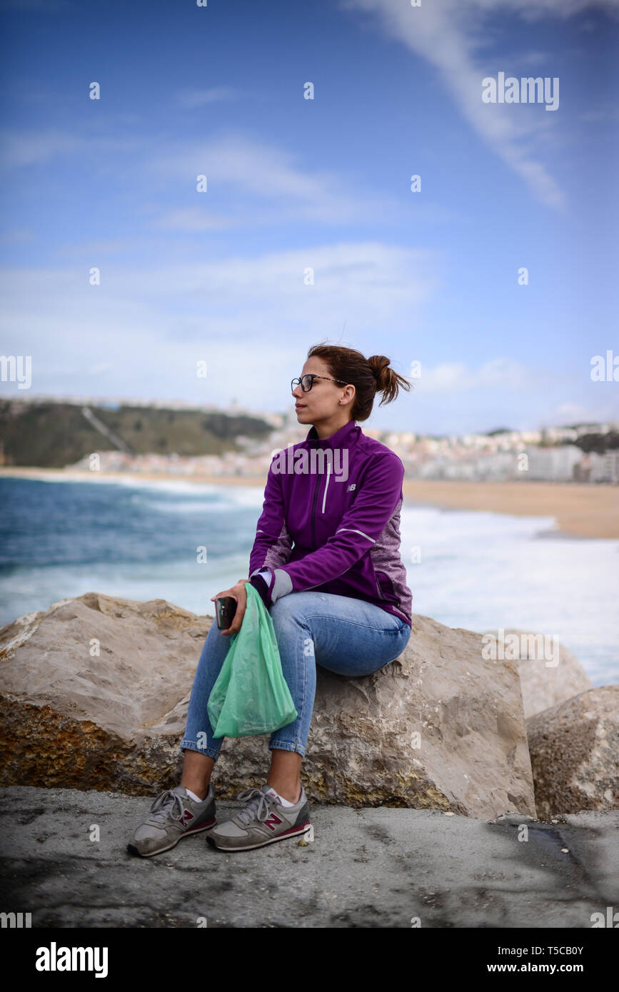 Young woman watches the sea from the dock of Nazare, Portugal Stock ...