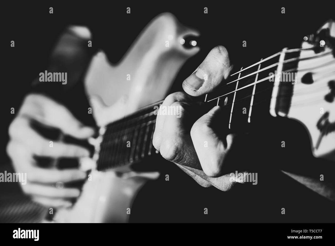 Man playing electric guitar close up. Black and white. Practicing ...