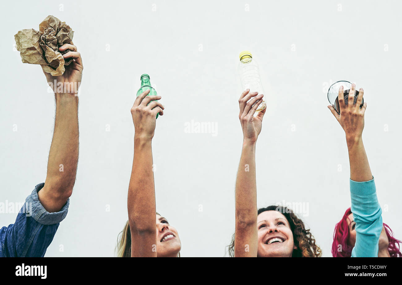 Happy people holding recyclable objects as paper, glass, plastic ...