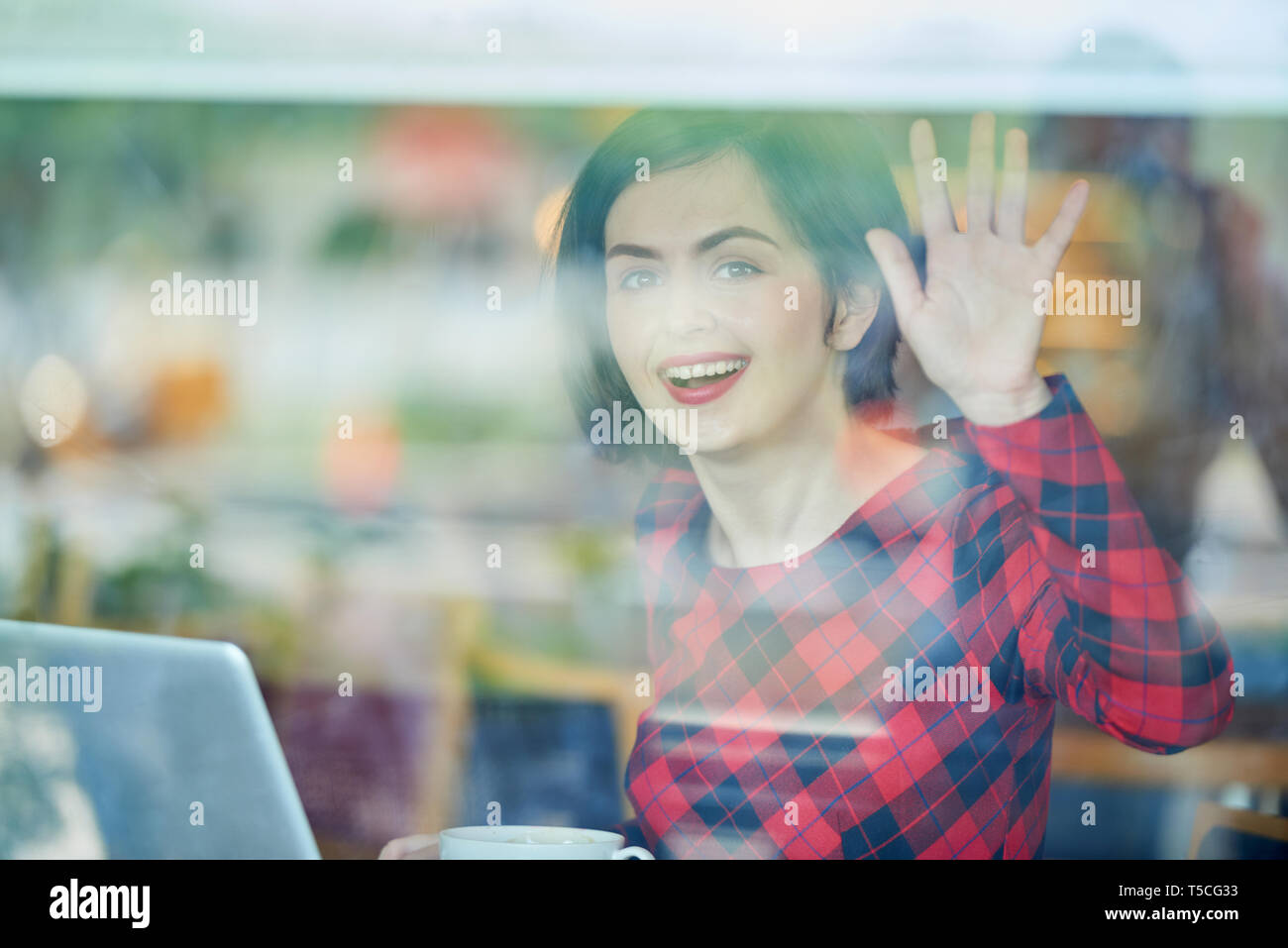 Pretty woman waving at camera Stock Photo - Alamy