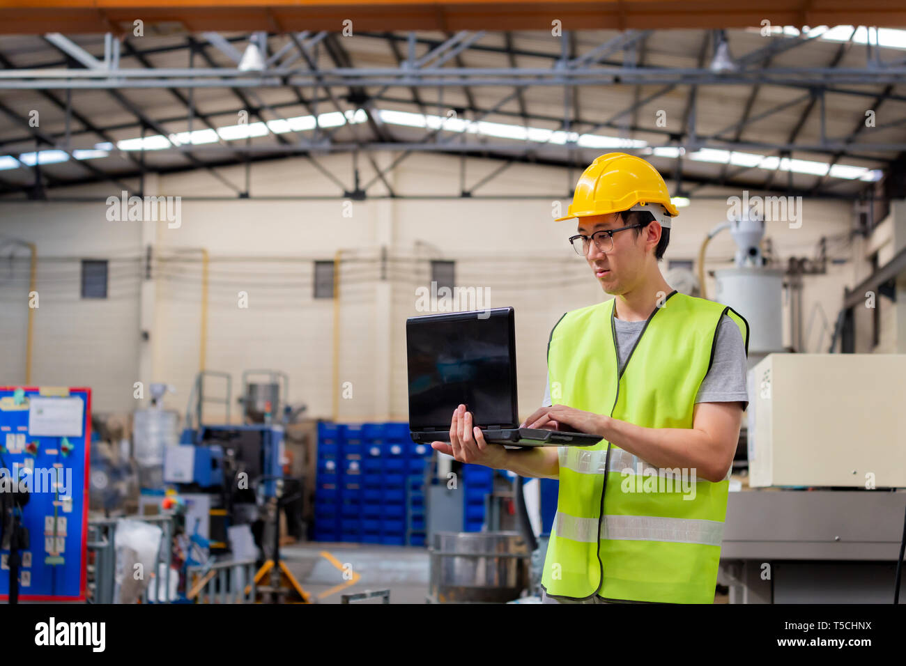 Asian male Industrial engineer in hardhat working with laptop in safety ...