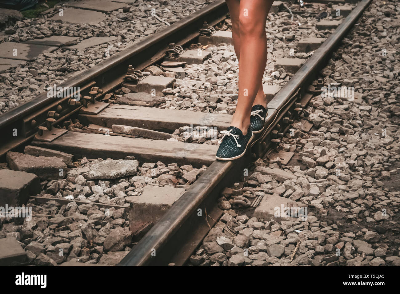 female legs in sneakers on the rail of railway Stock Photo - Alamy